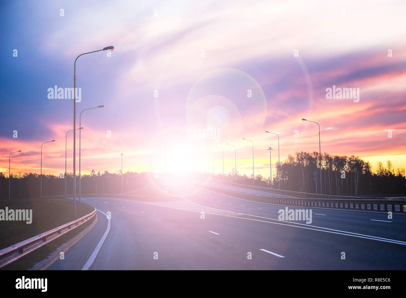 Interchange of the highway. Dramatic sky, fiery sunset. The lights on ...