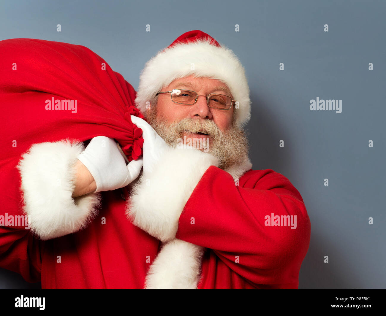 Santa Claus is holding a huge bag of gifts on his shoulder. Christmas ...
