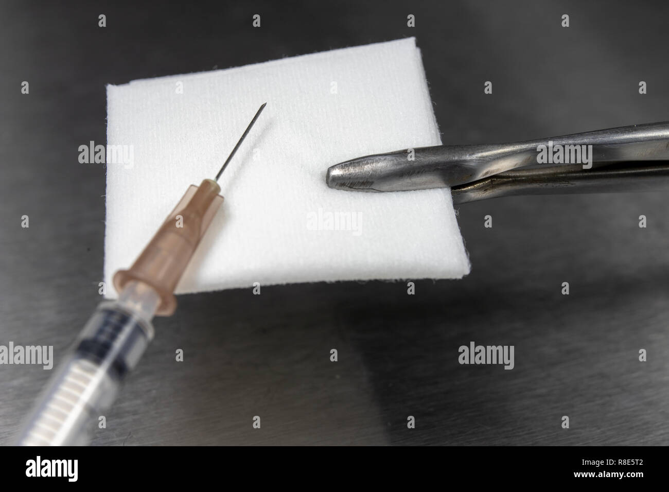 Sterile swab, pliers and a medical syringe on a hospital table ...