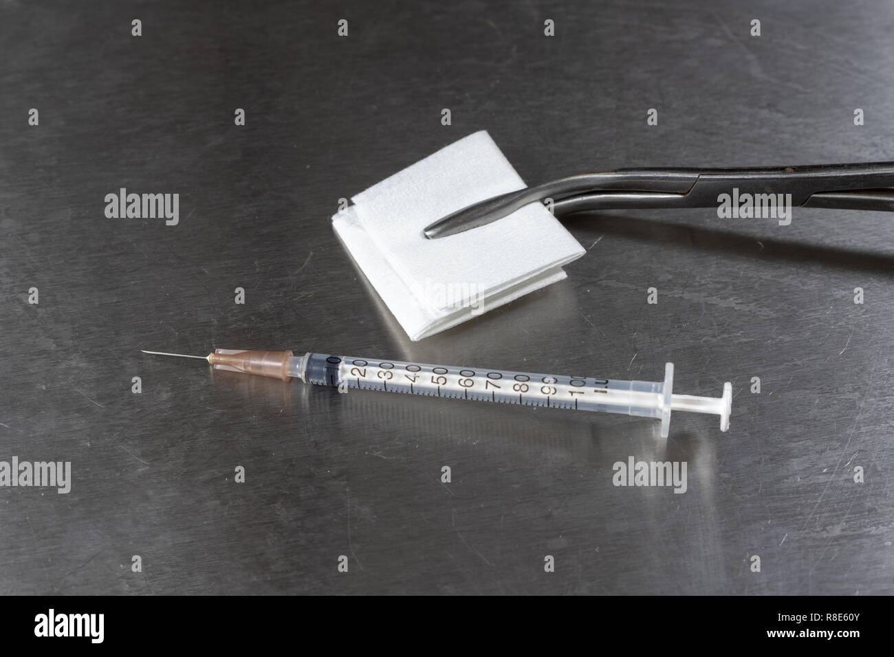 Sterile swab, pliers and a medical syringe on a hospital table ...