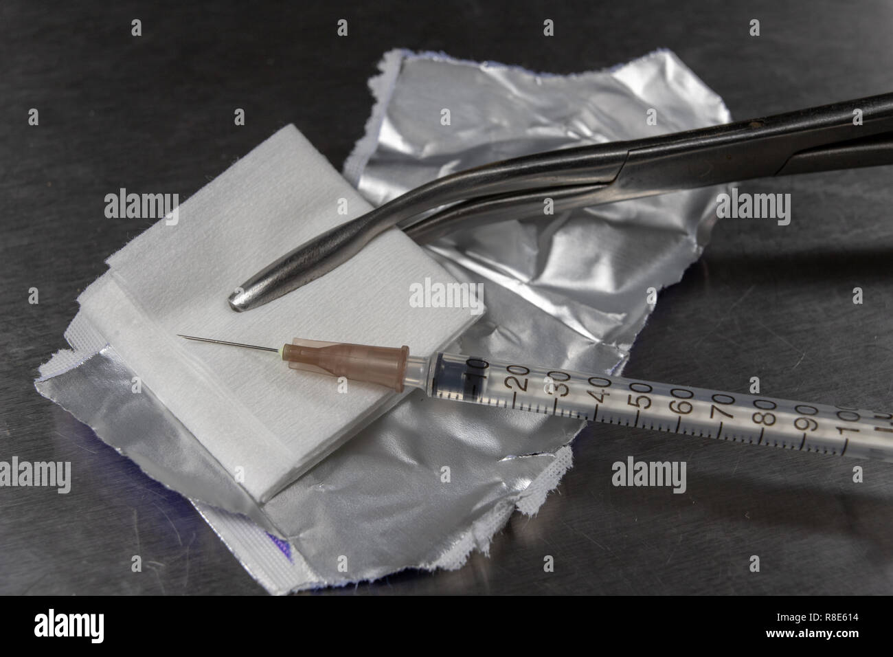 Sterile swab, pliers and a medical syringe on a hospital table ...