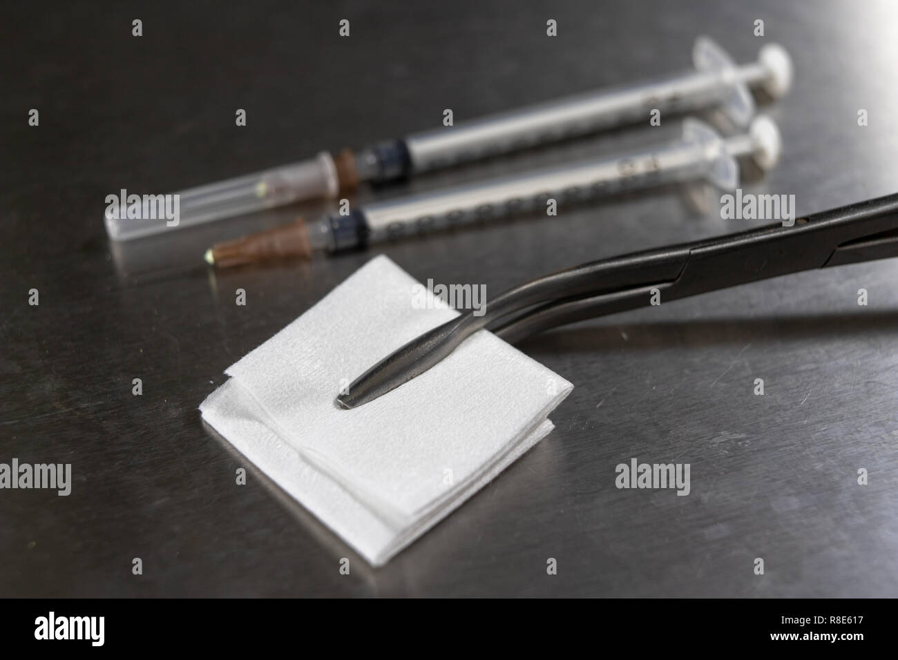 Sterile swab, pliers and a medical syringe on a hospital table ...
