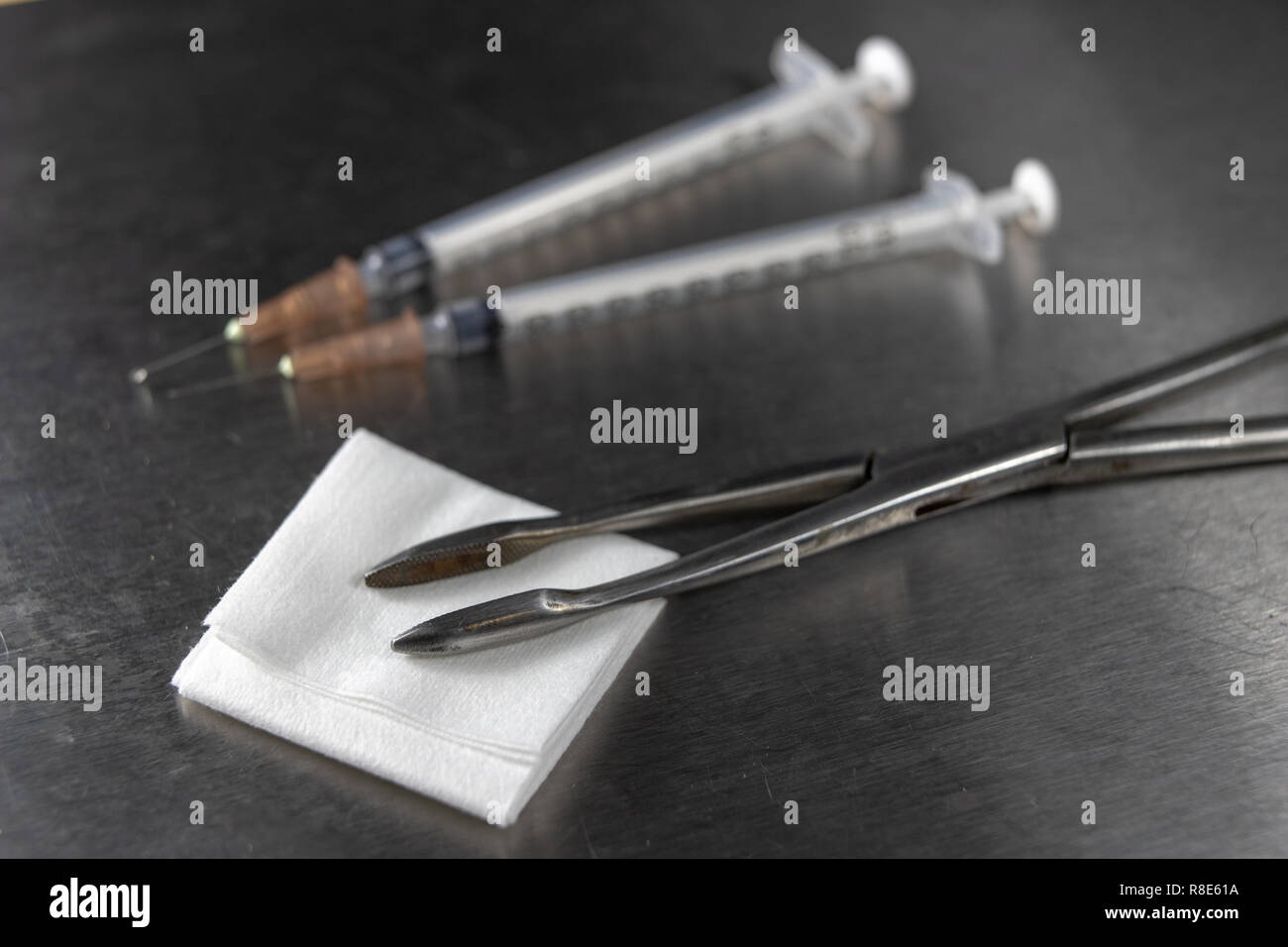 Sterile swab, pliers and a medical syringe on a hospital table ...