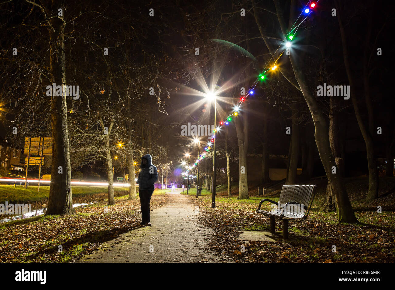 solitary figure, stood on path, in public park at night time during ...