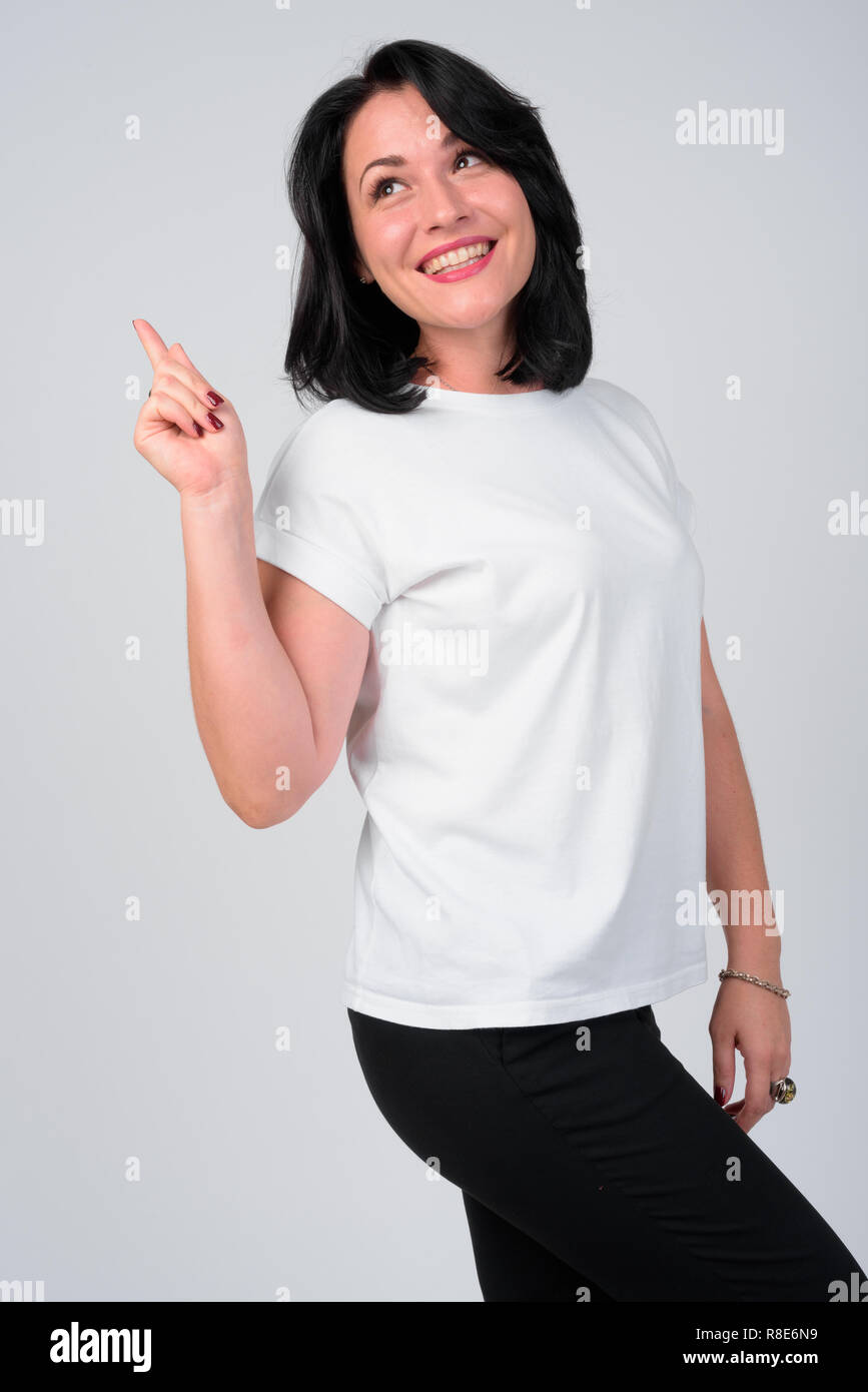 Happy beautiful woman thinking and pointing up against white background ...