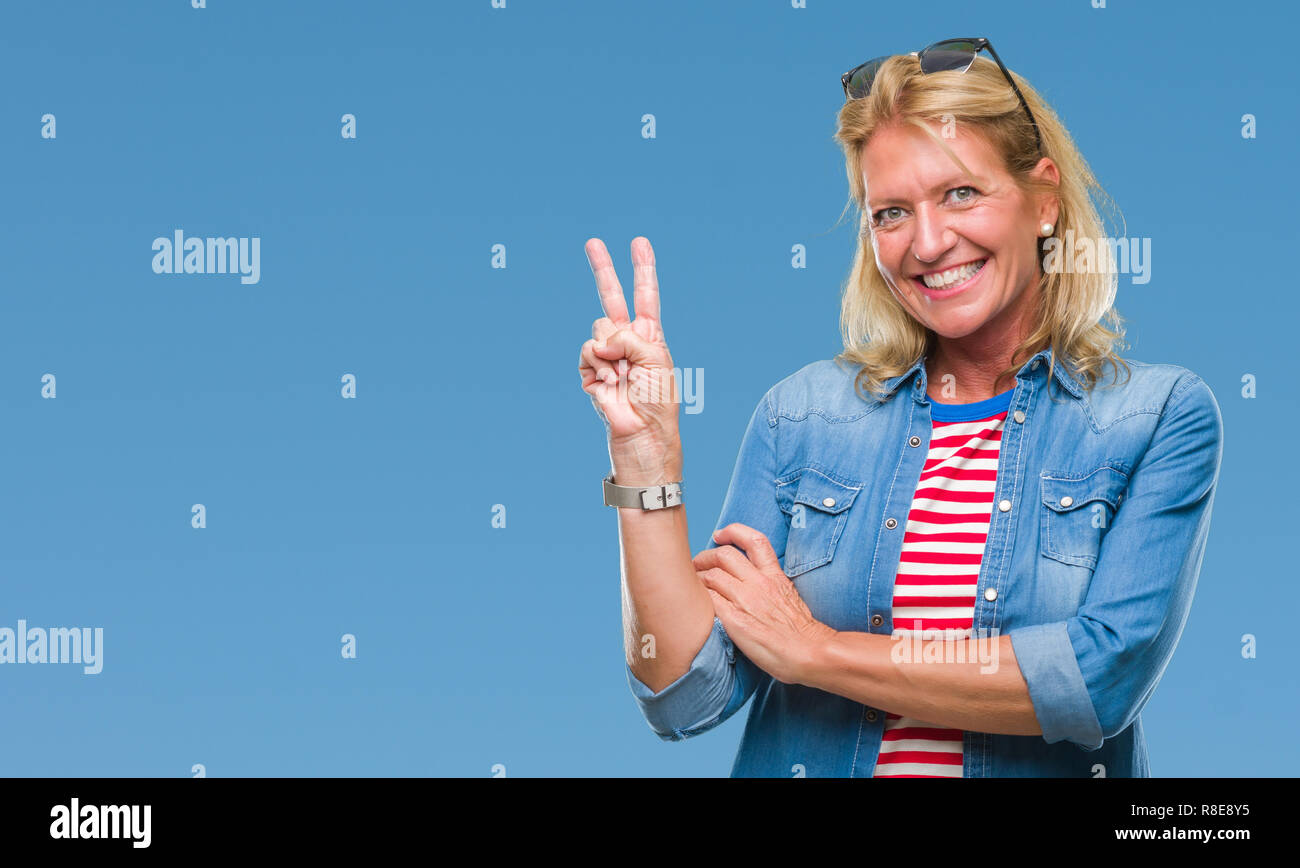 Middle age blonde woman over isolated background smiling with happy face winking at the camera ...