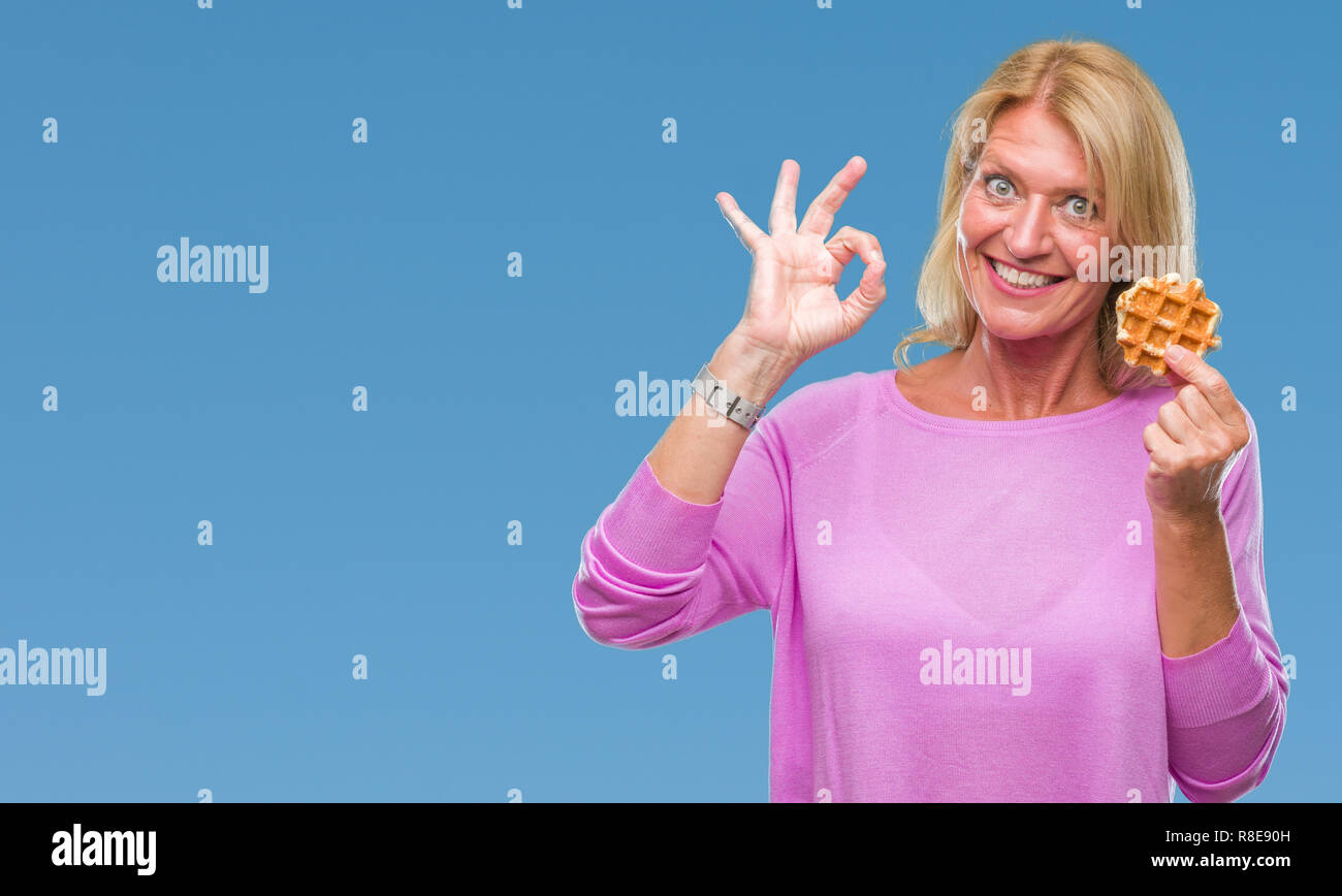 Middle age blonde woman eating sweet waffle over isolated background ...