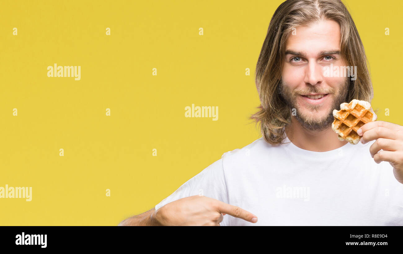 Young handsome man with long hair over isolated background eating ...
