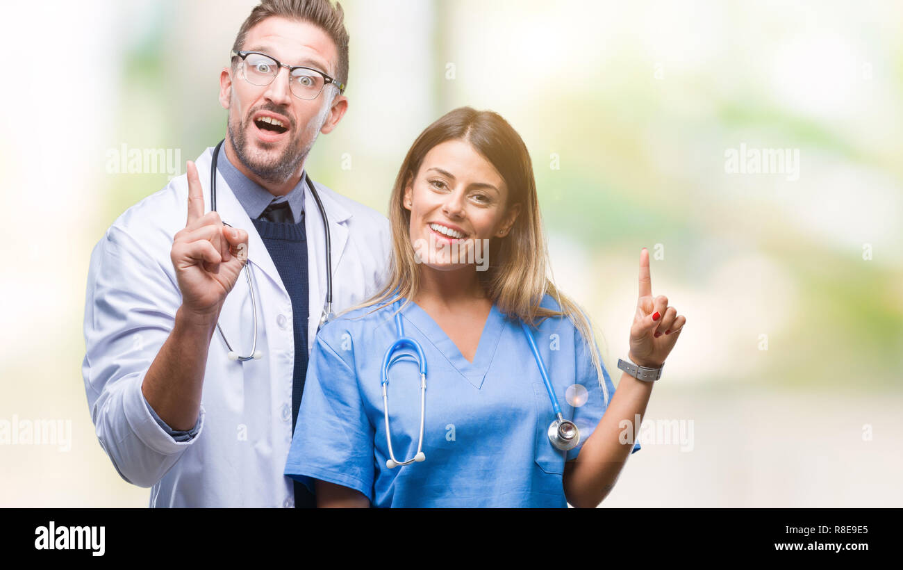 Young couple of doctor and surgeon over isolated background pointing ...
