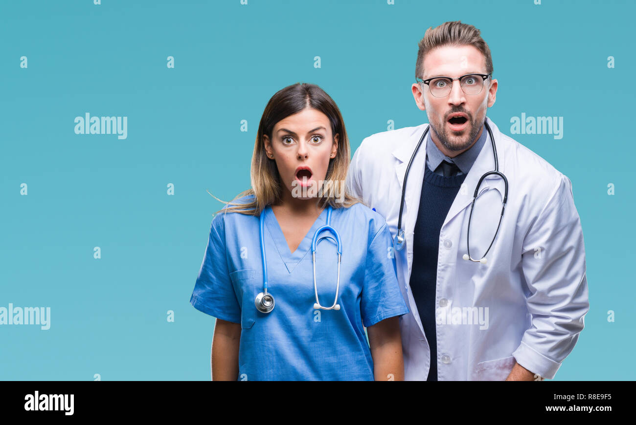 Young couple of doctor and surgeon over isolated background afraid and ...