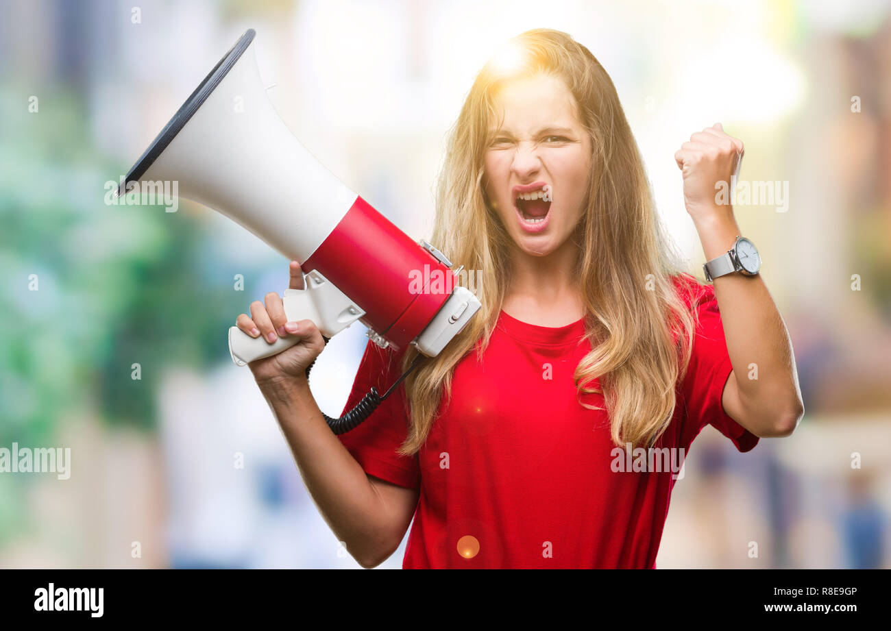 Young beautiful blonde woman yelling through megaphone over isolated ...