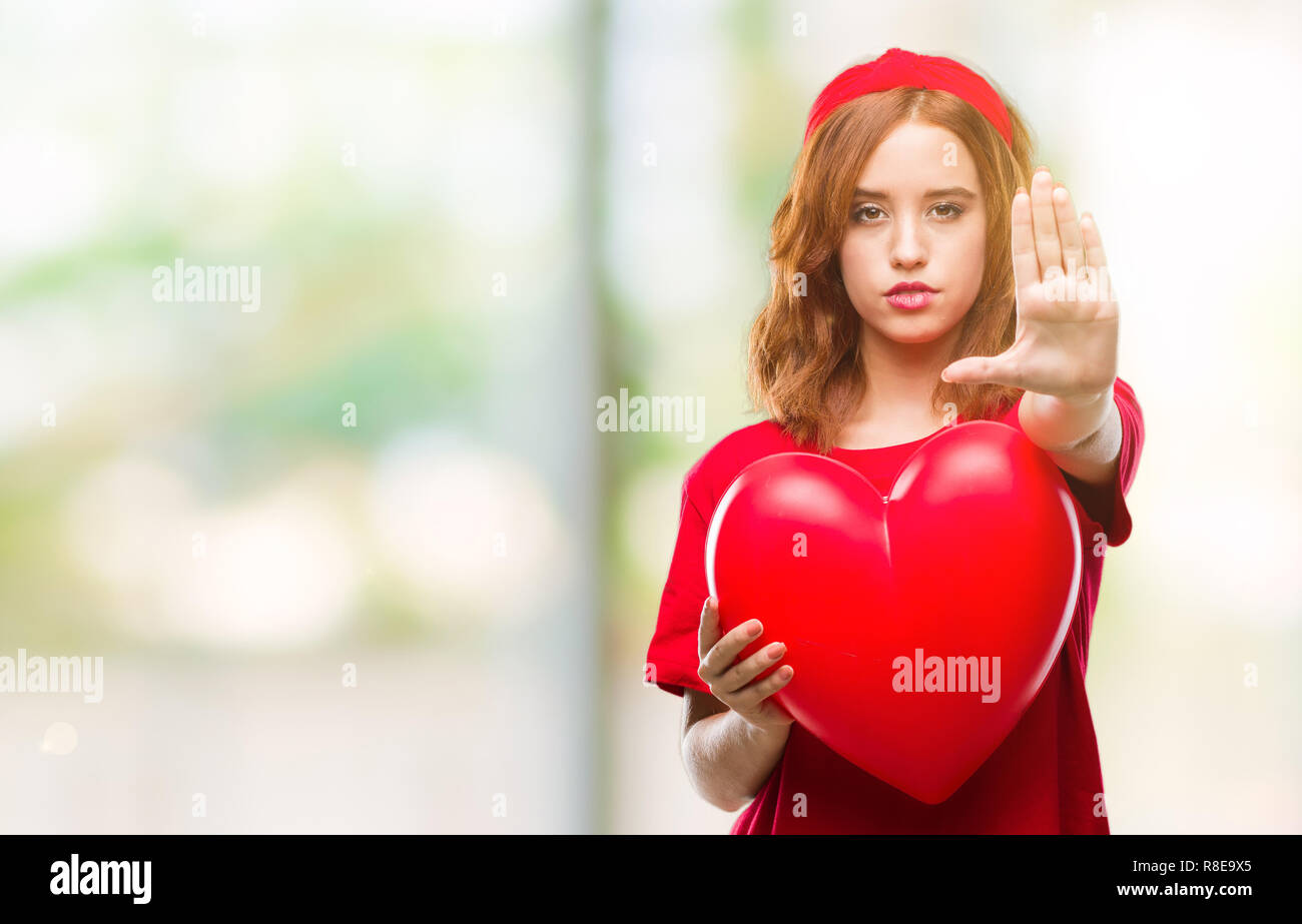 Young beautiful woman holding red heart in love over isolated ...