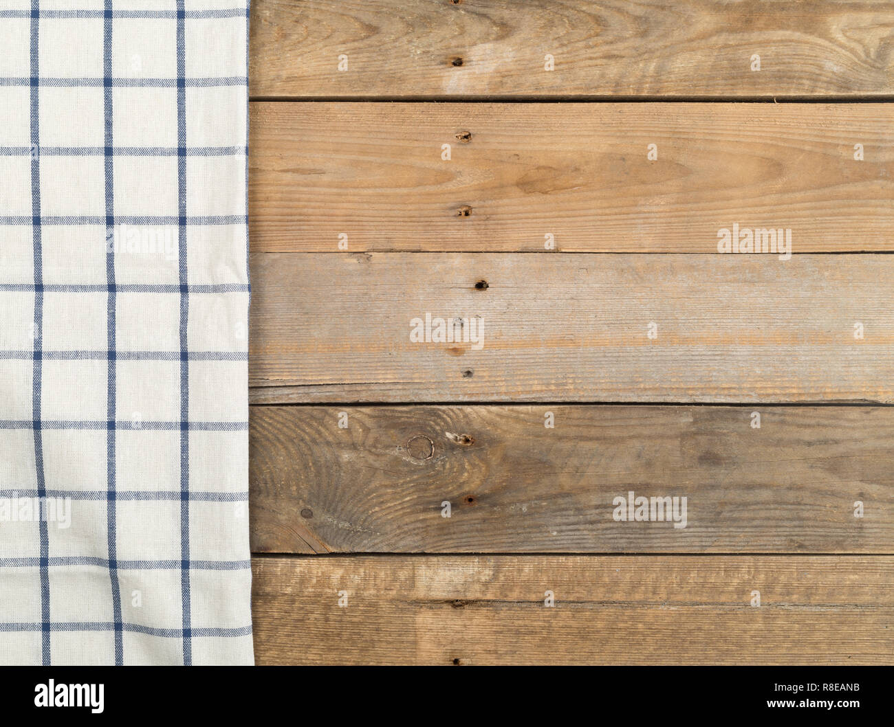 Blue and white checkered dishcloth on brown rustic wooden plank table ...