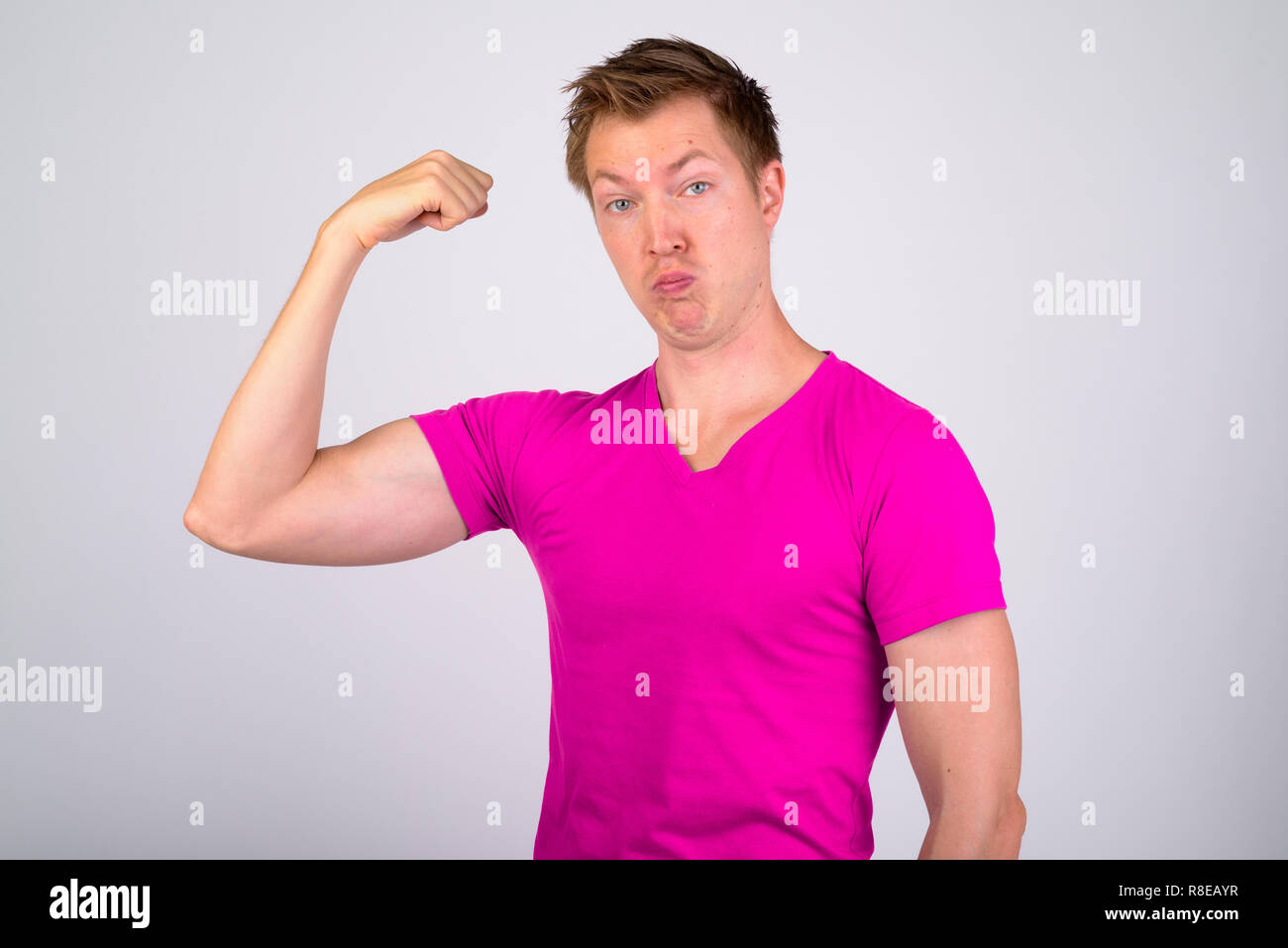 Funny young man making face while flexing muscles Stock Photo - Alamy