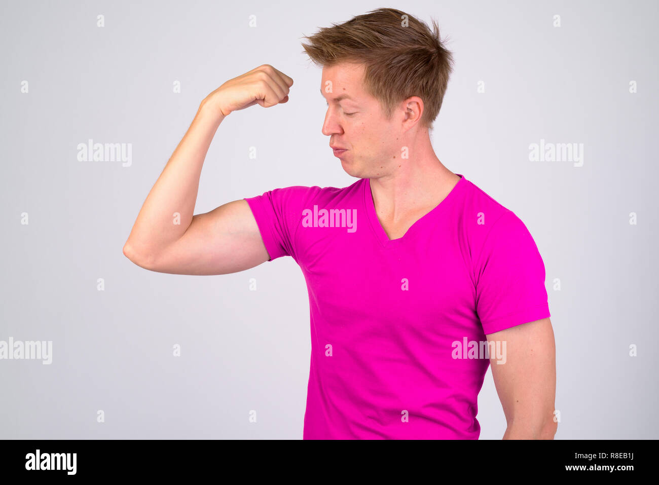Young funny looking man making face while flexing muscles Stock Photo ...