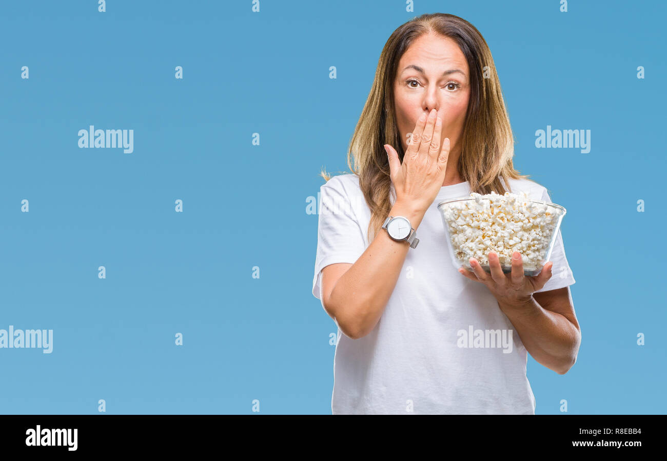 Middle age hispanic woman eating popcorn over isolated background cover ...