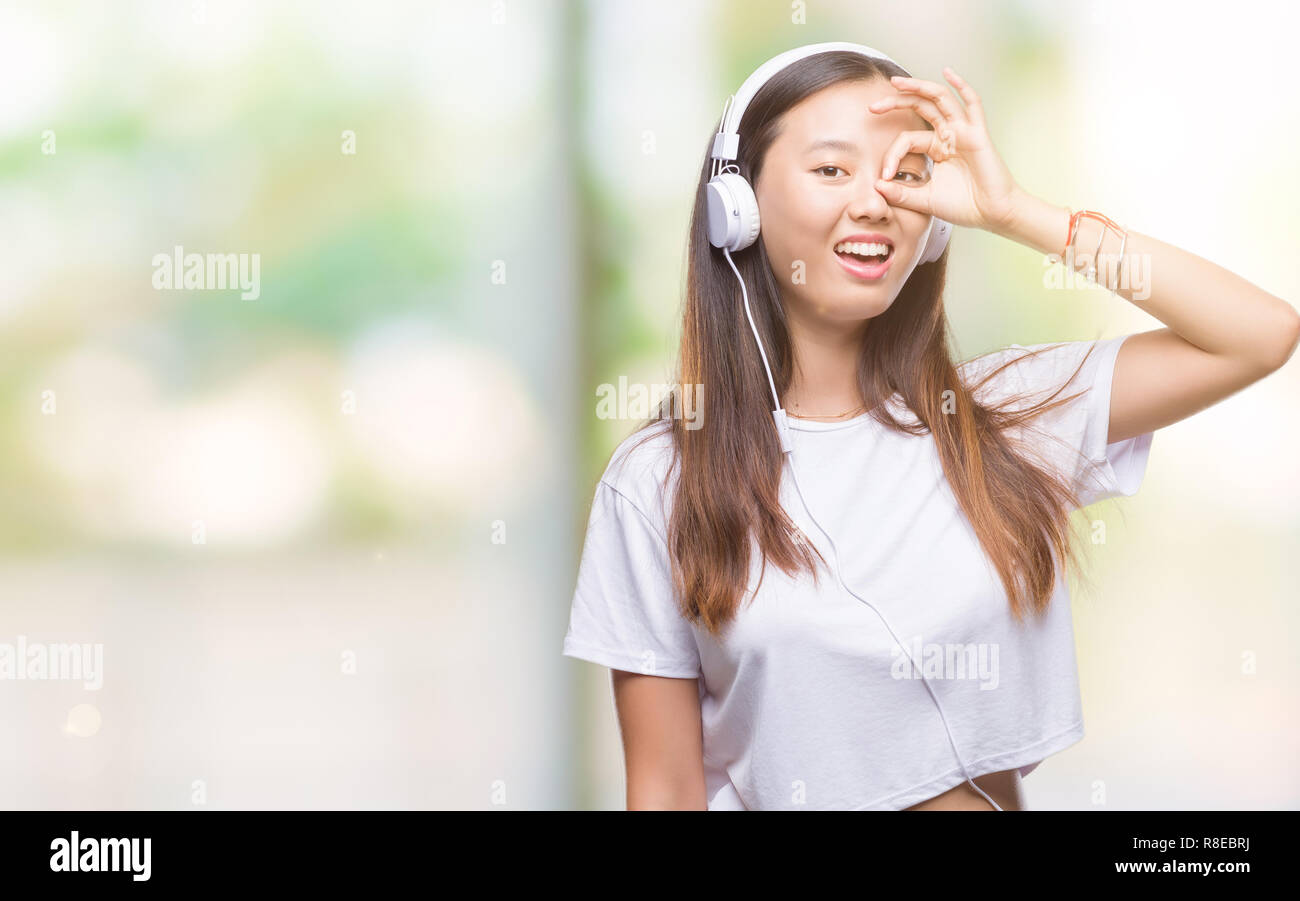 Young asian woman listening to music wearing headphones isolated ...