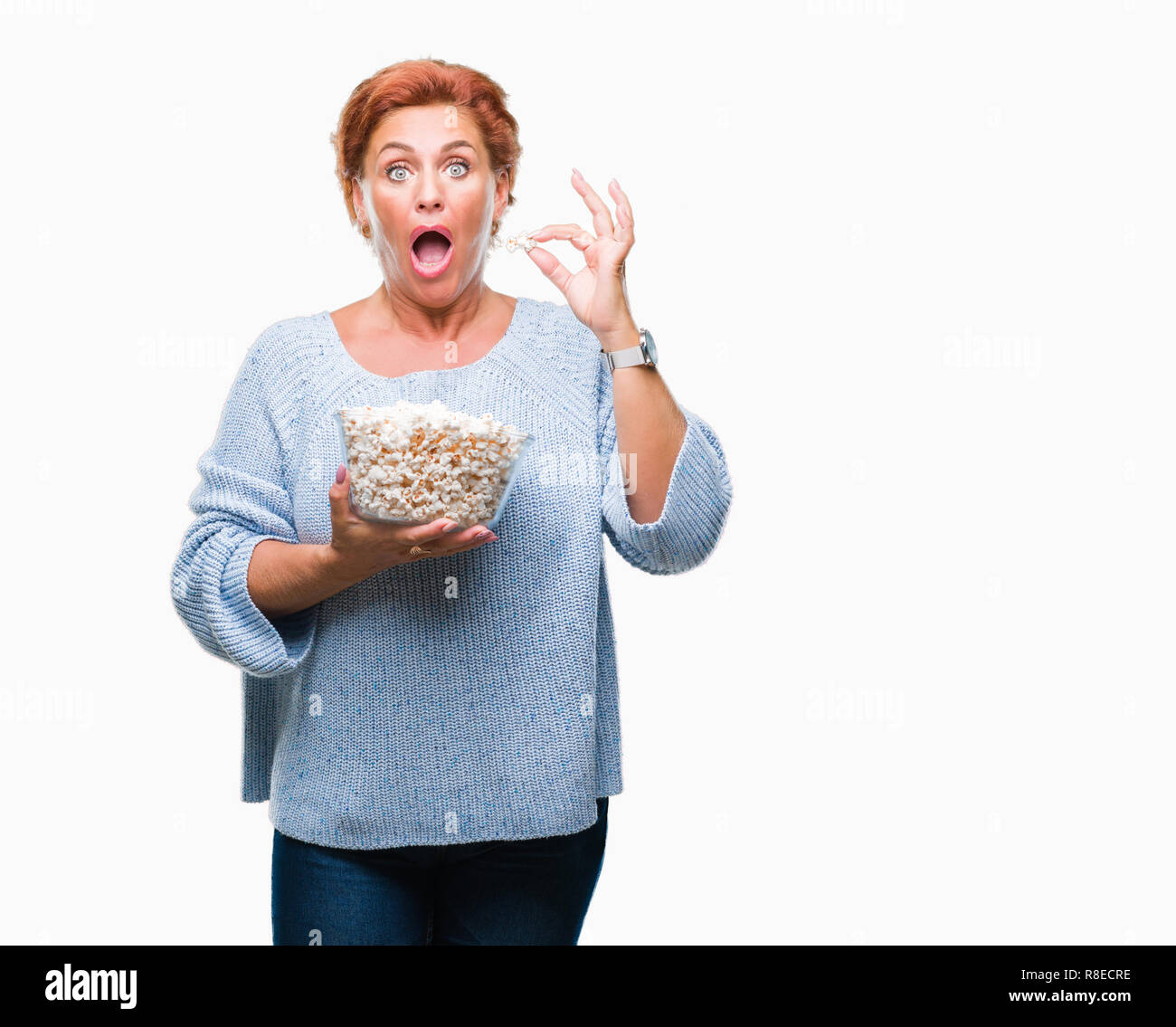 Atrractive senior caucasian redhead woman eating popcorn over isolated ...