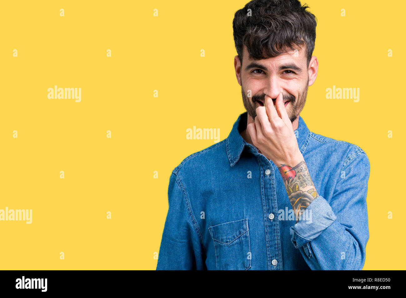 Young handsome man over isolated background smelling something stinky ...