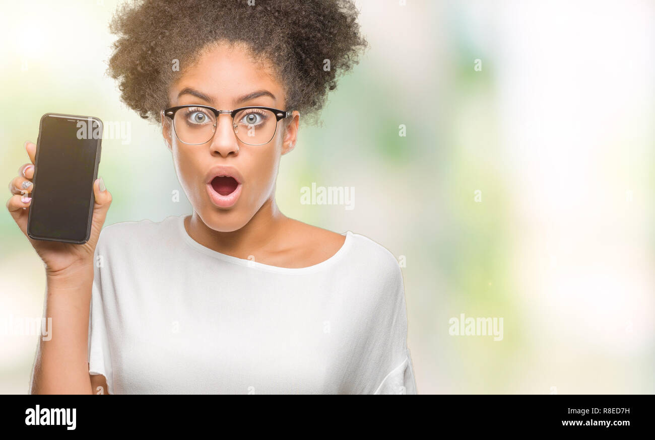 Young beautiful afro american showing smartphone screen over isolated ...