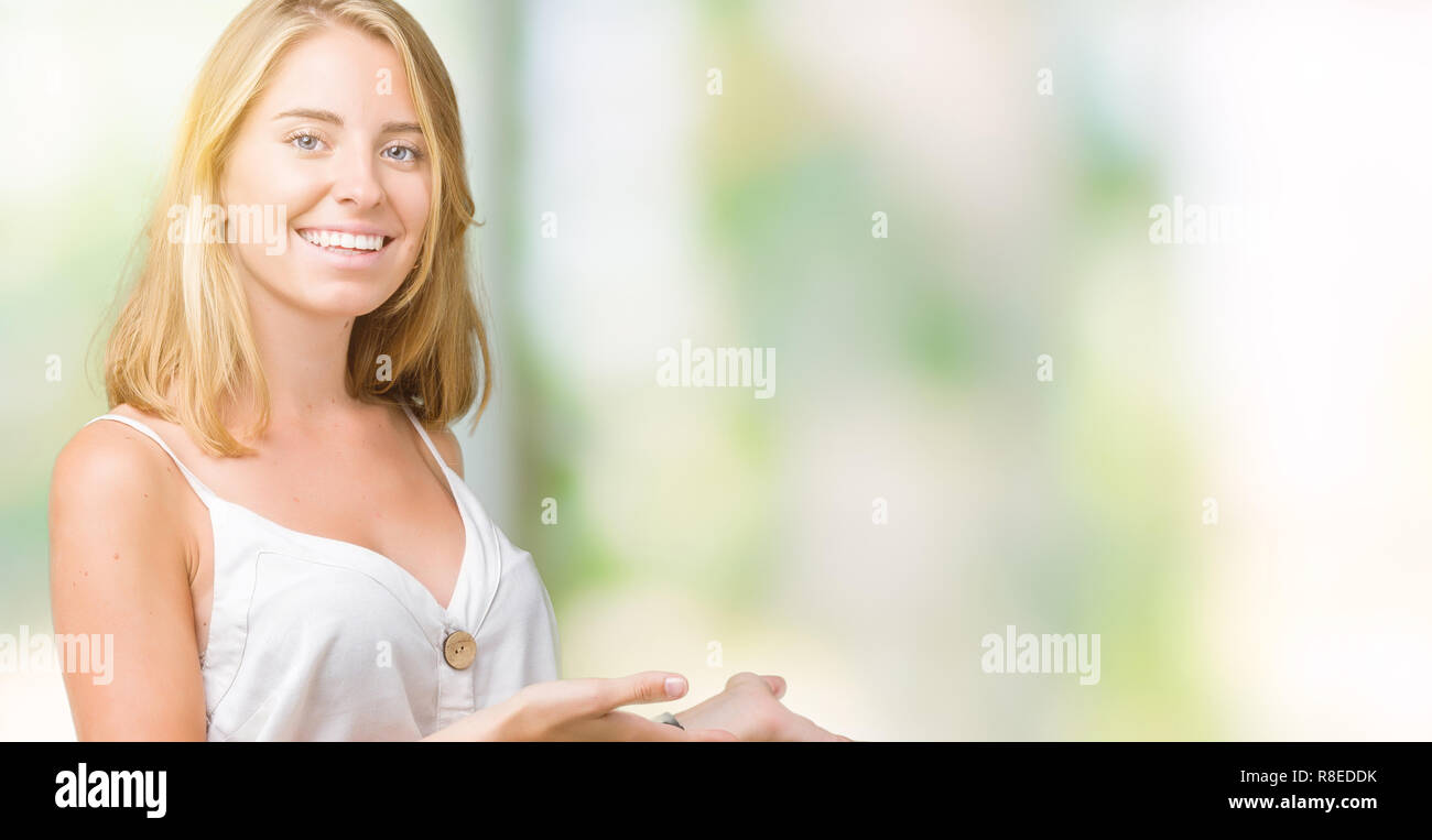 Beautiful young woman over isolated background Inviting to enter ...