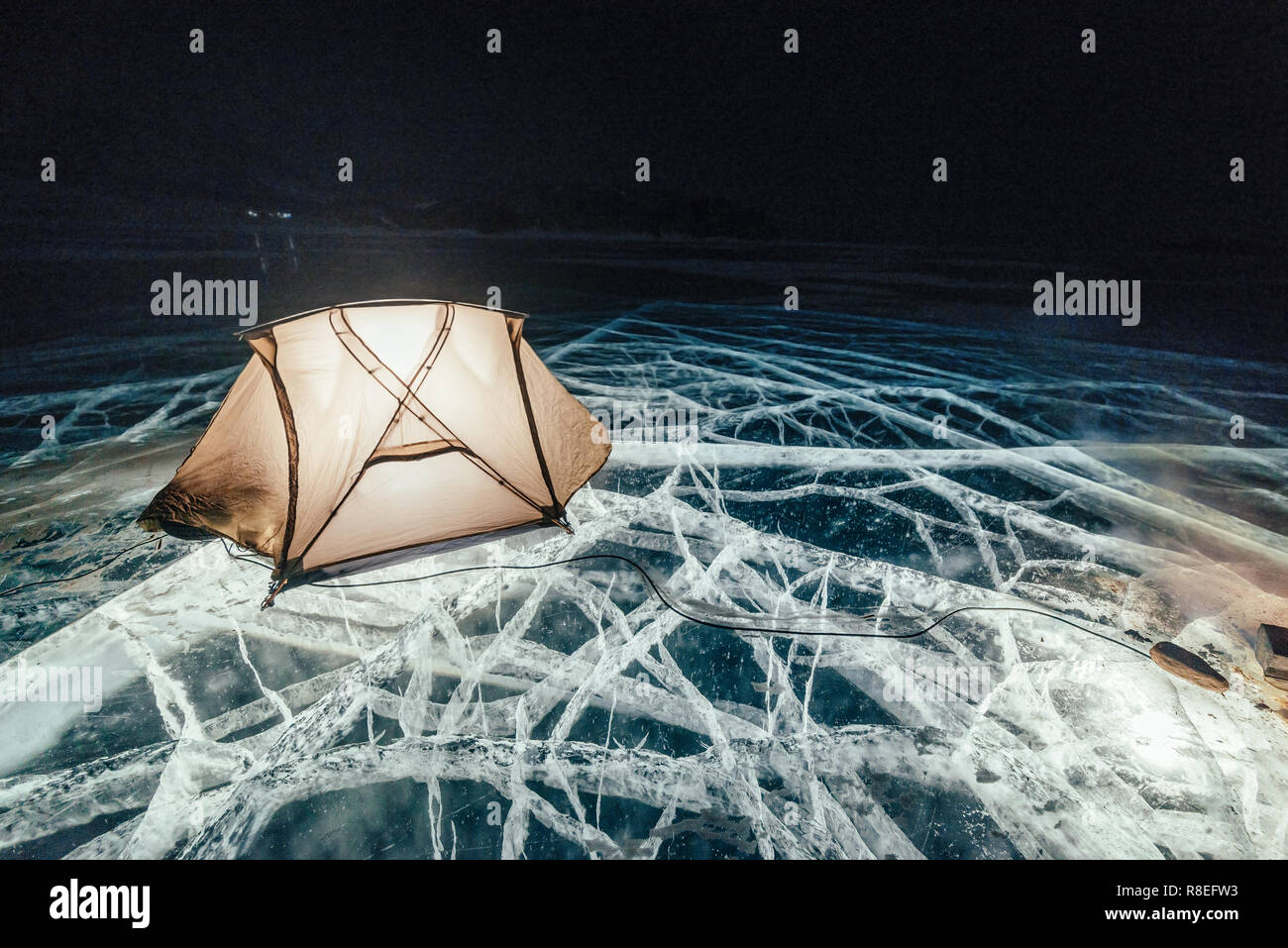 Fire on ice at night. Campground on ice. Tent stands next to bonfire ...