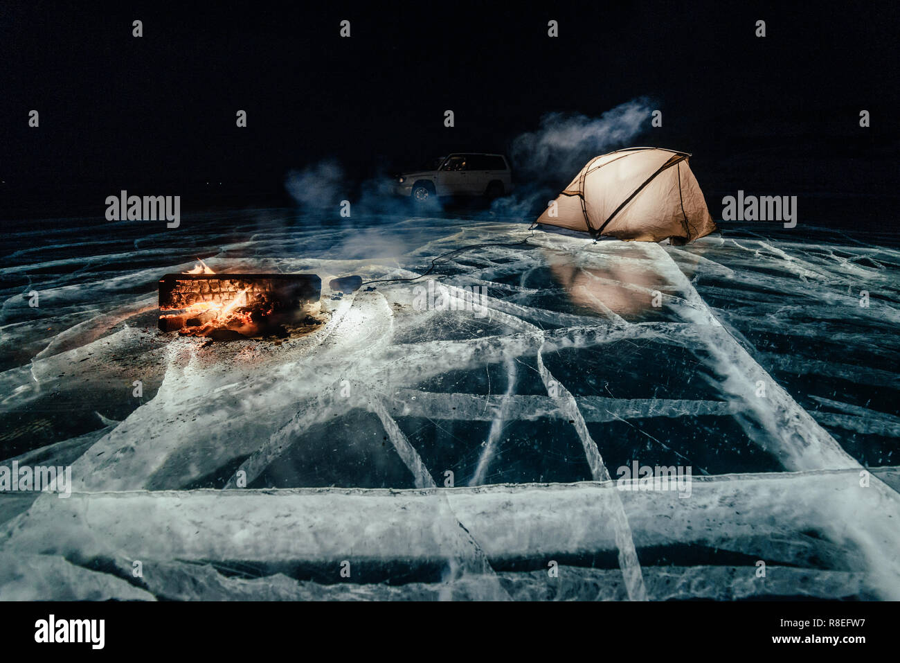 Fire on ice at night. Campground on ice. Tent stands next to bonfire ...