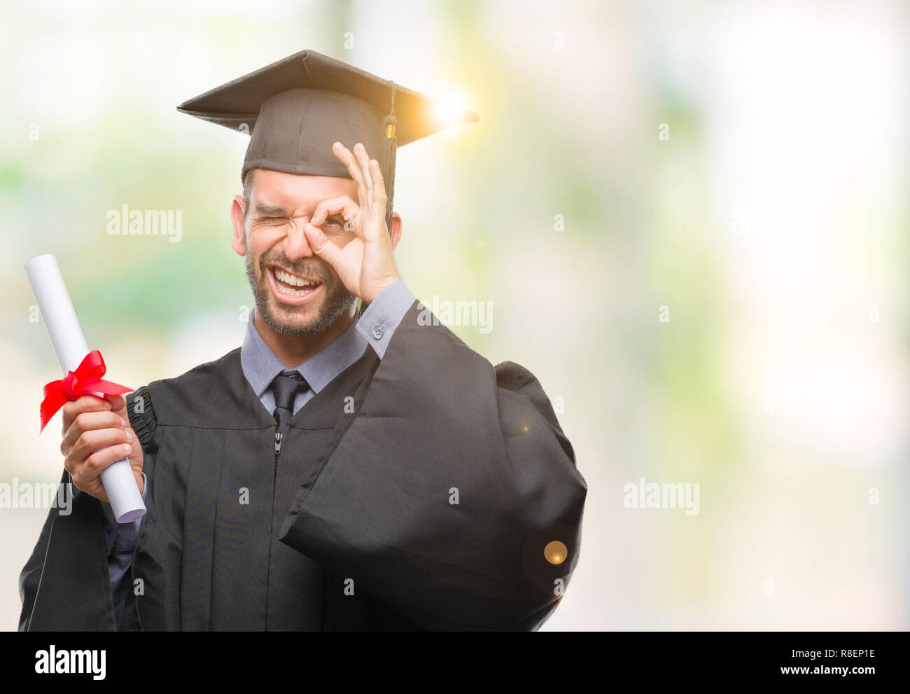 Young handsome graduated man holding degree over isolated background ...