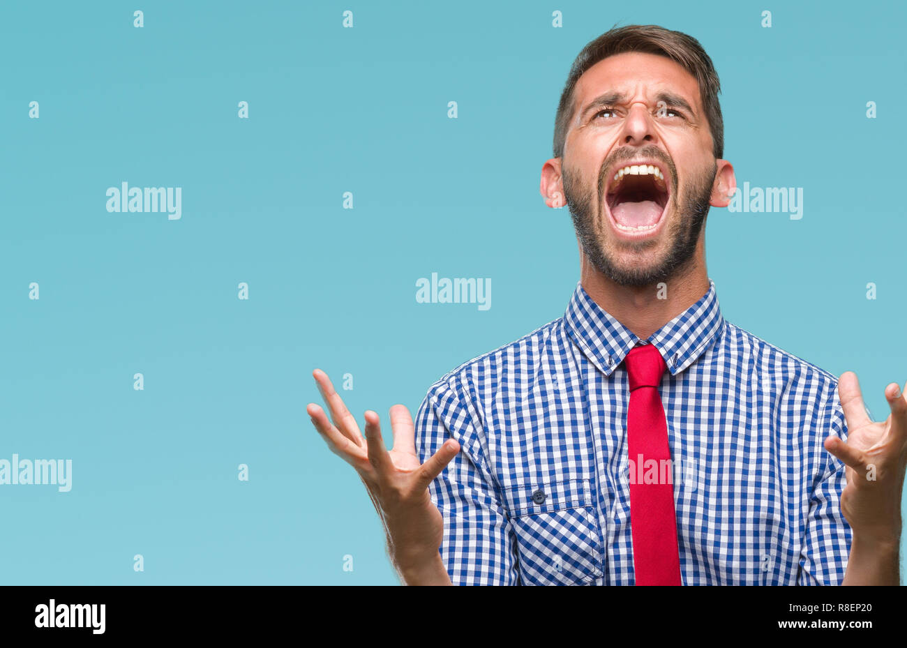 Young handsome business man over isolated background crazy and mad ...