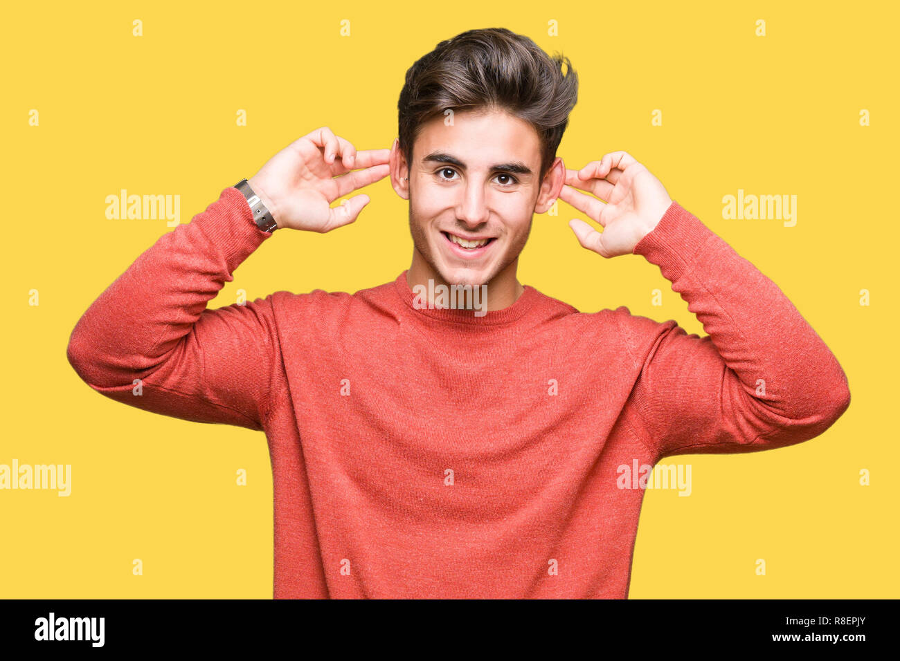 Young handsome man over isolated background Smiling pulling ears with ...