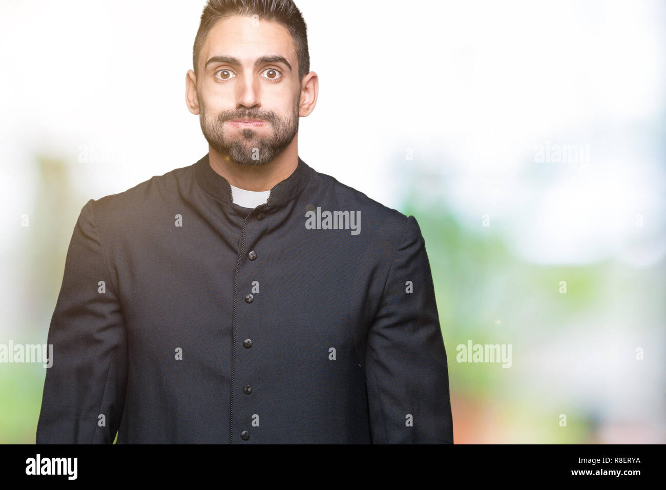 Young Christian priest over isolated background puffing cheeks with ...