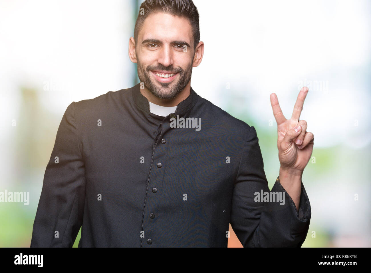 Young Christian priest over isolated background smiling with happy face ...