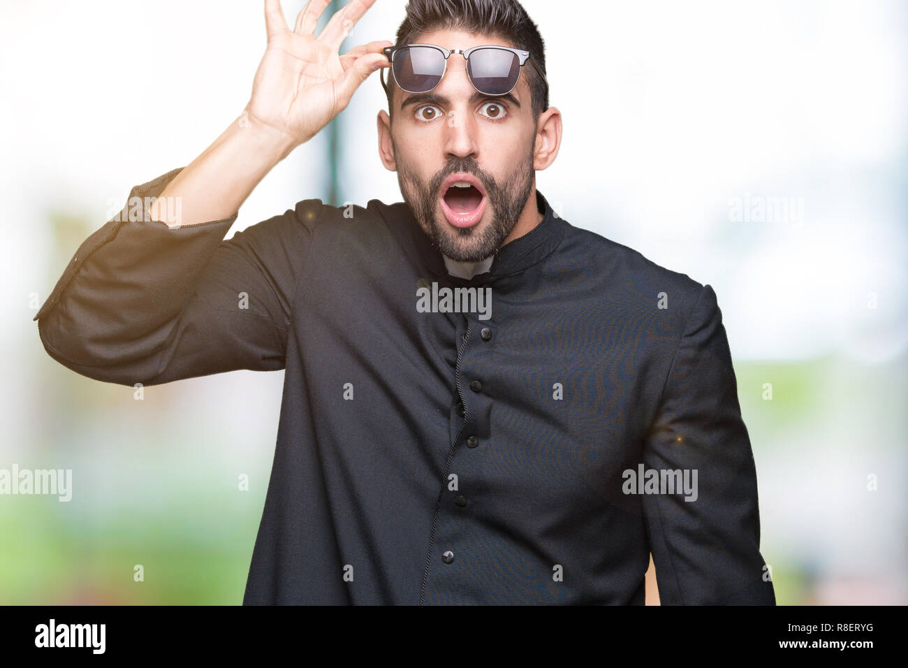 Young Christian priest wearing sunglasses over isolated background ...