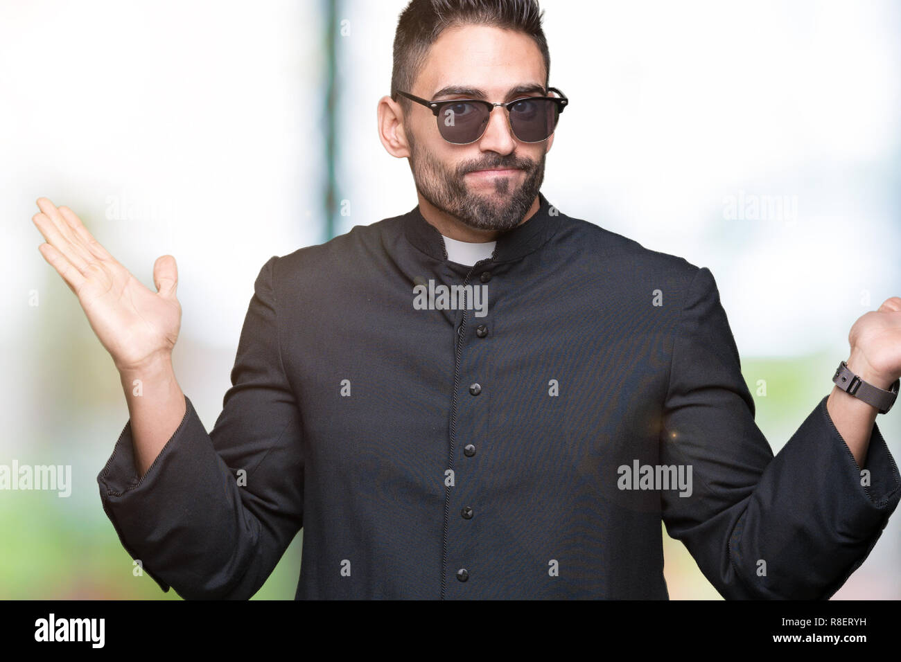 Young Christian priest wearing sunglasses over isolated background ...