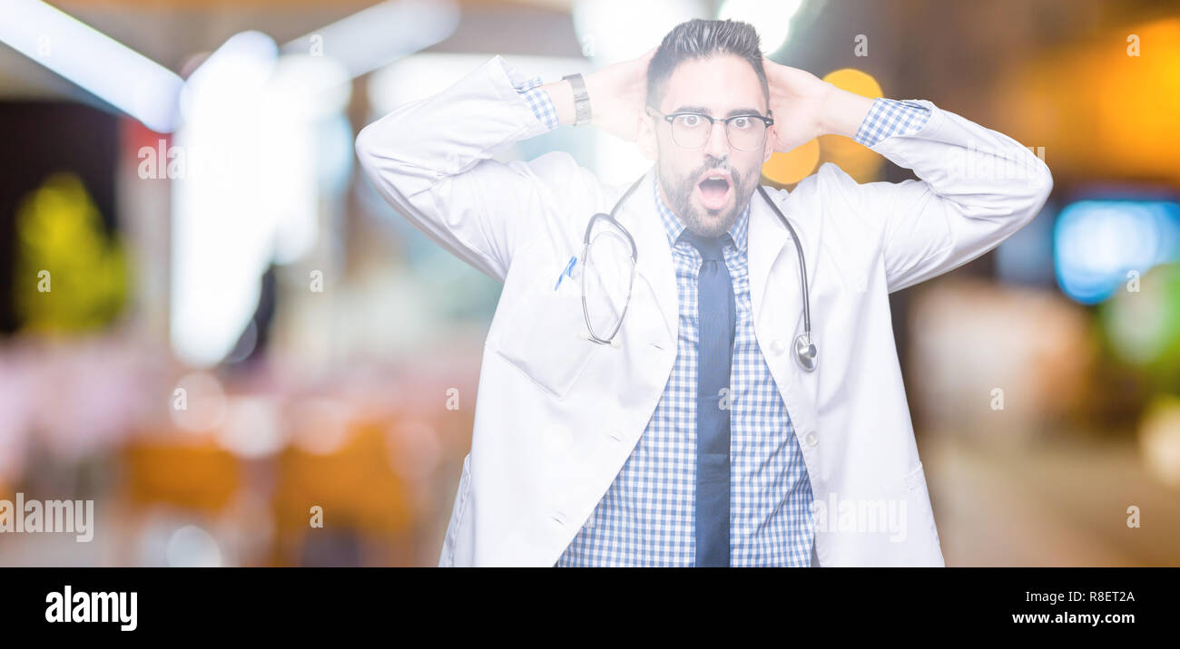 Handsome young doctor man over isolated background Crazy and scared ...