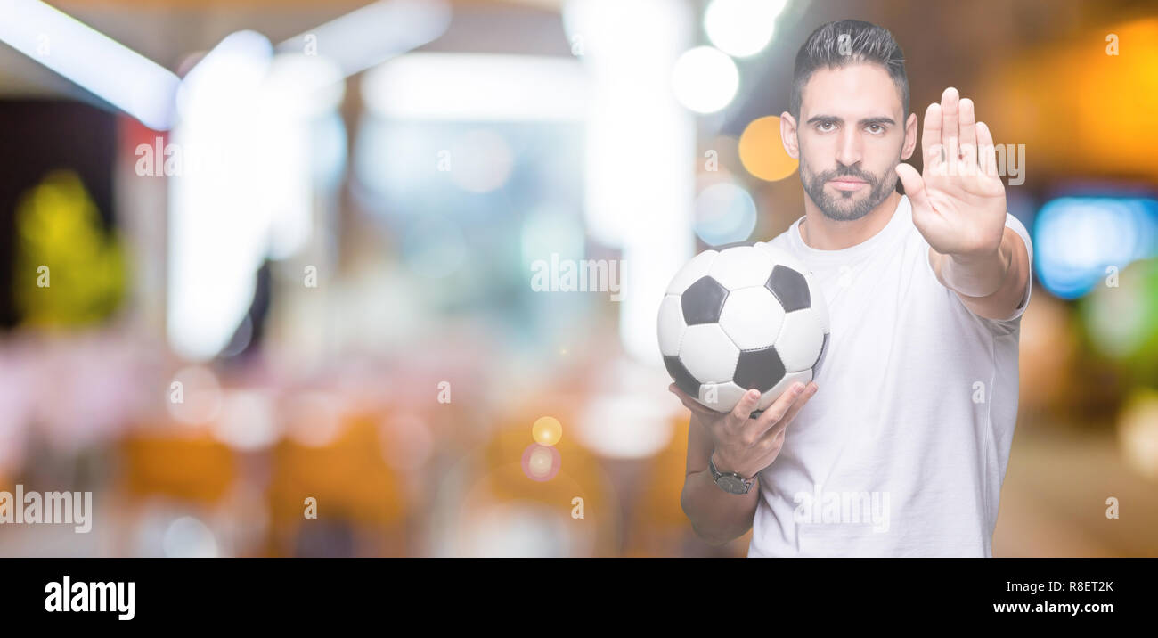 Young man holding soccer football ball over isolated background with ...
