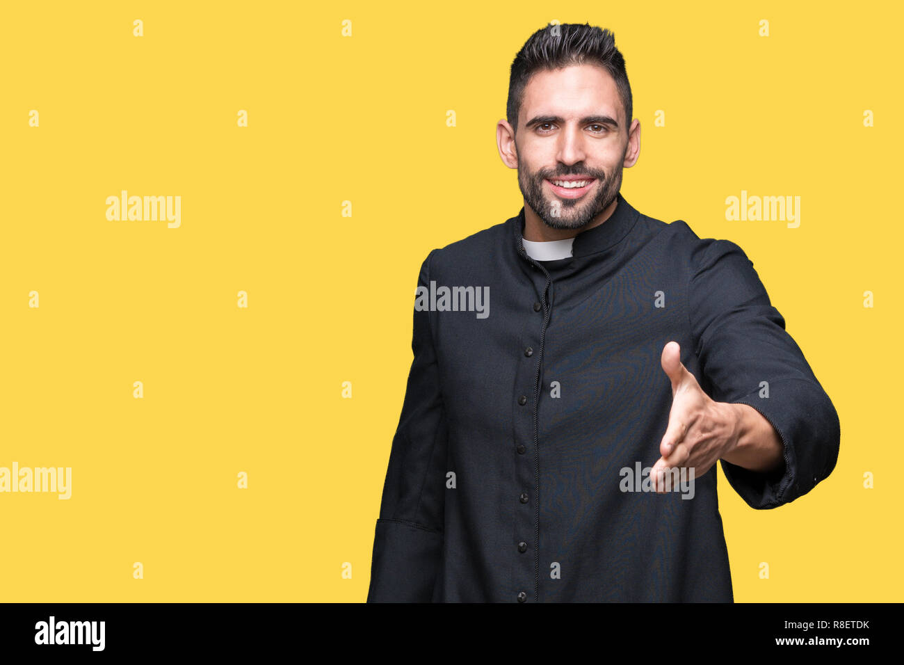 Young Christian priest over isolated background smiling friendly ...