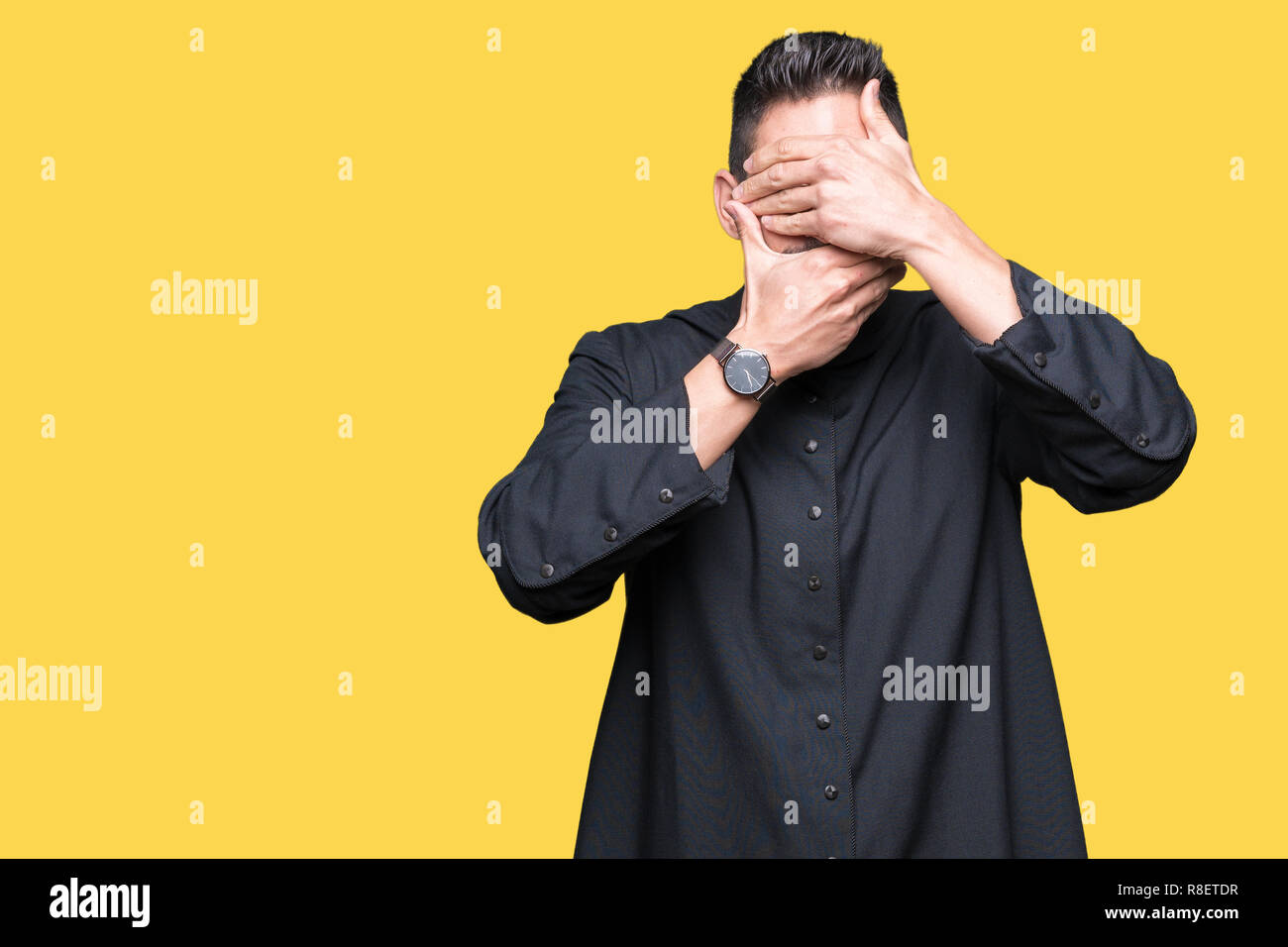 Young Christian priest over isolated background Covering eyes and mouth ...