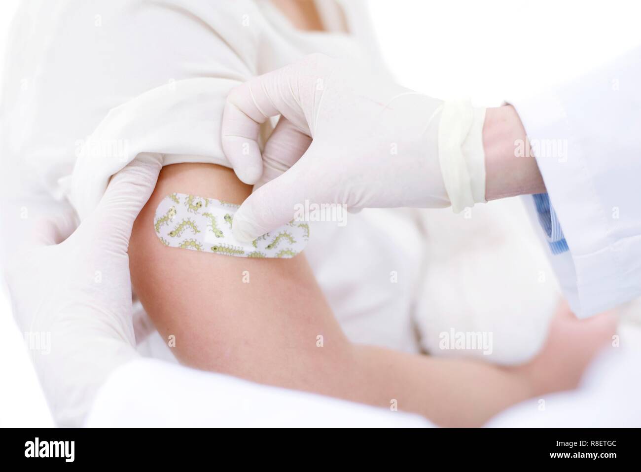 Doctor sticking plaster on young girl's arm after injection Stock Photo ...