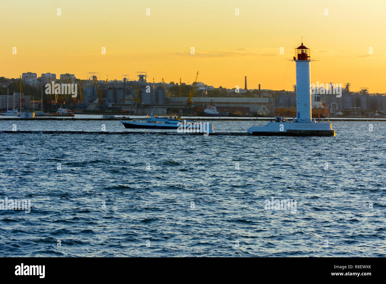 A lighthouse in the sea at the entrance to the port against the ...