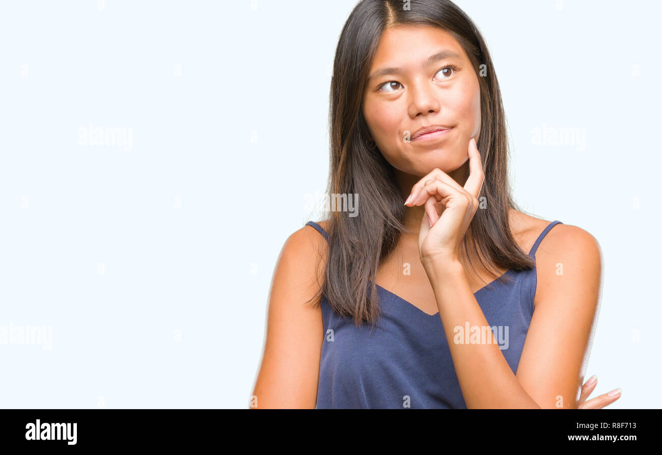 Young asian woman over isolated background with hand on chin thinking ...