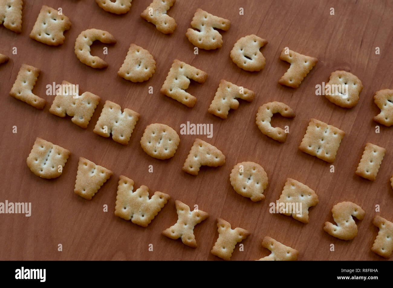 Letters of salty crackers lay on a wooden brown surface in the order ...