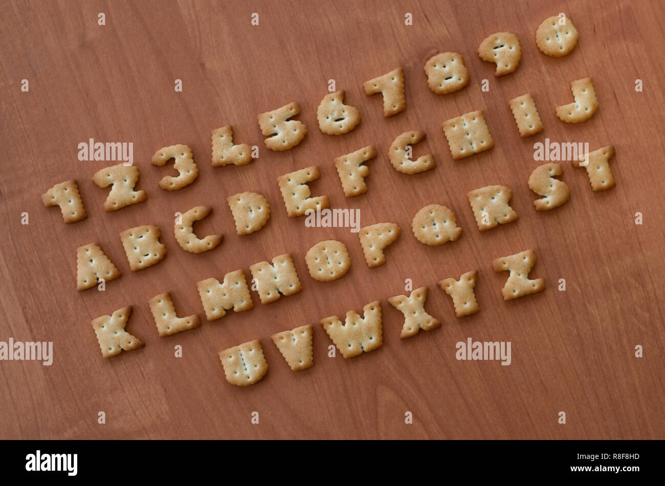 Letters of salty crackers lay on a wooden brown surface in the order ...