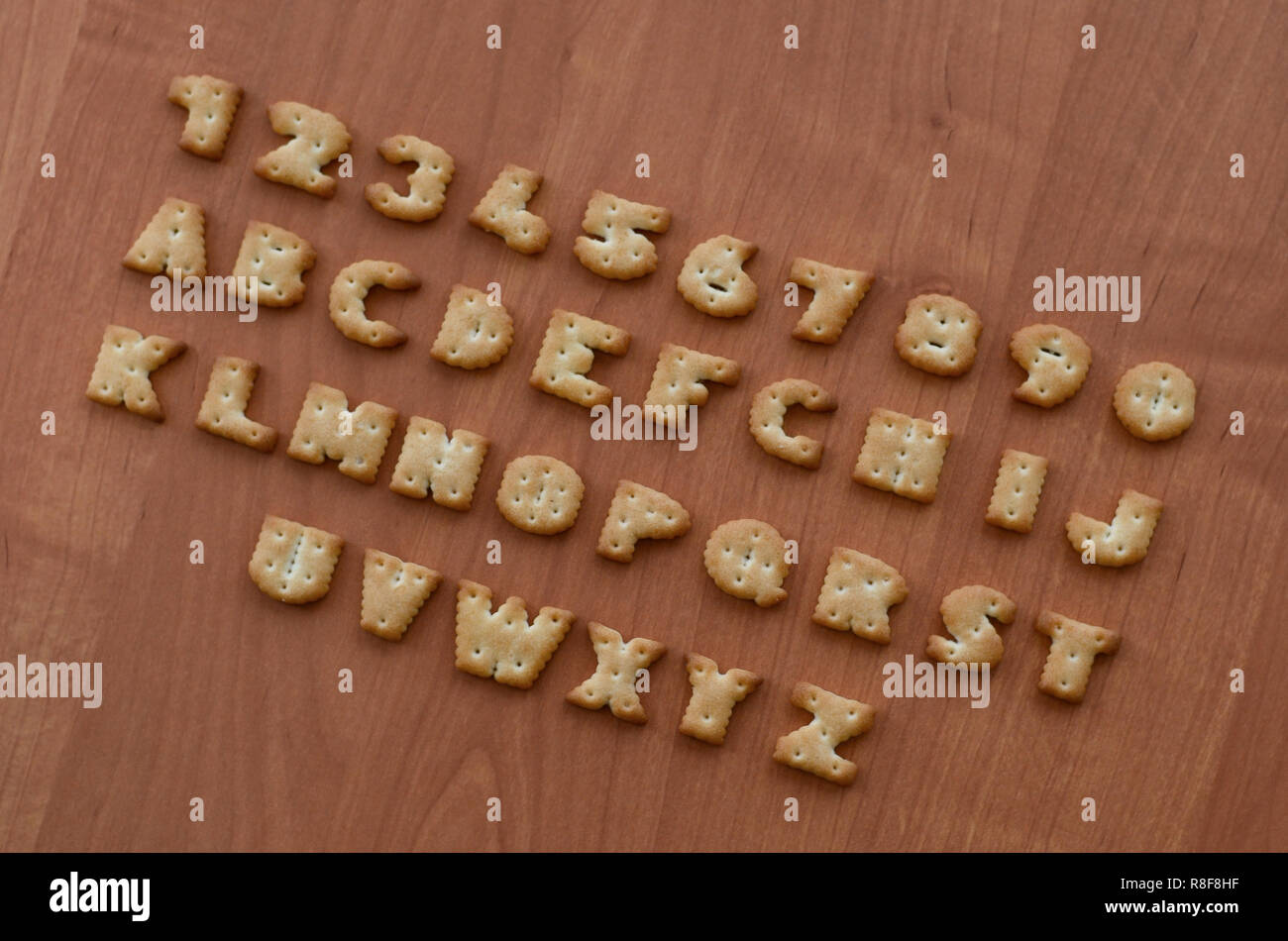 Letters of salty crackers lay on a wooden brown surface in the order ...