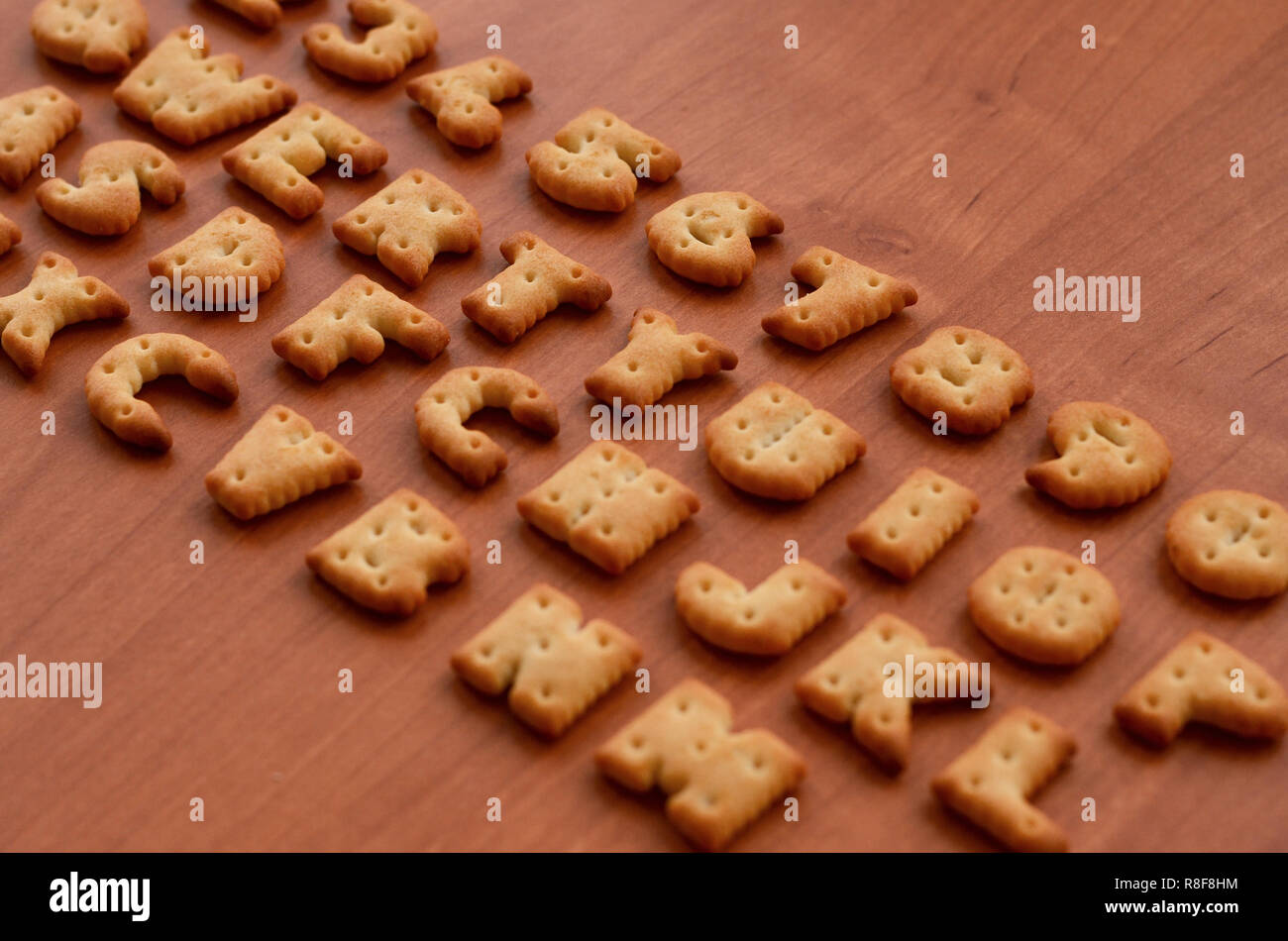 Letters of salty crackers lay on a wooden brown surface in the order ...