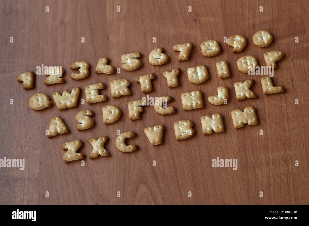 Letters of salty crackers lay on a wooden brown surface in the order ...