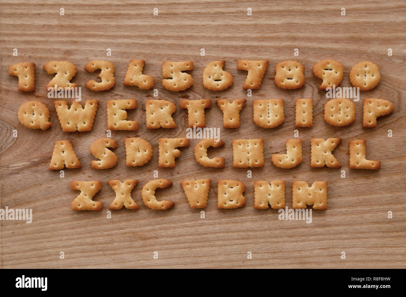Letters of salty crackers lay on a wooden brown surface in the order ...