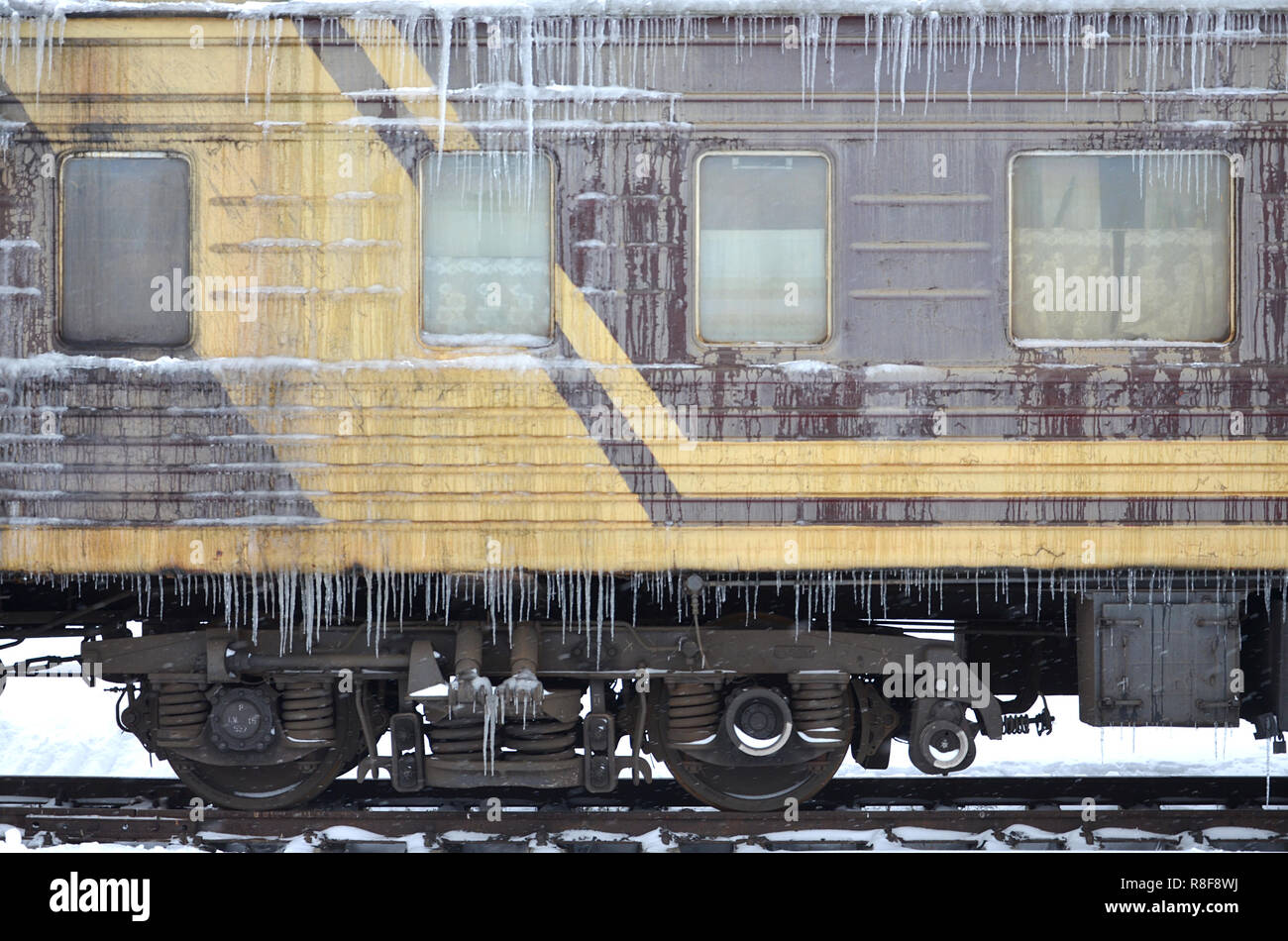 Detailed photo of a frozen car passenger train with icicles and ice on ...
