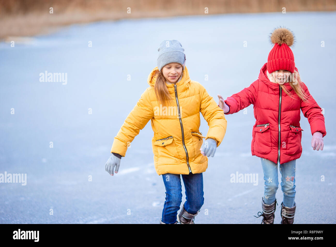 Adorable girls skating on ice rink outdoors in winter snow day Stock ...