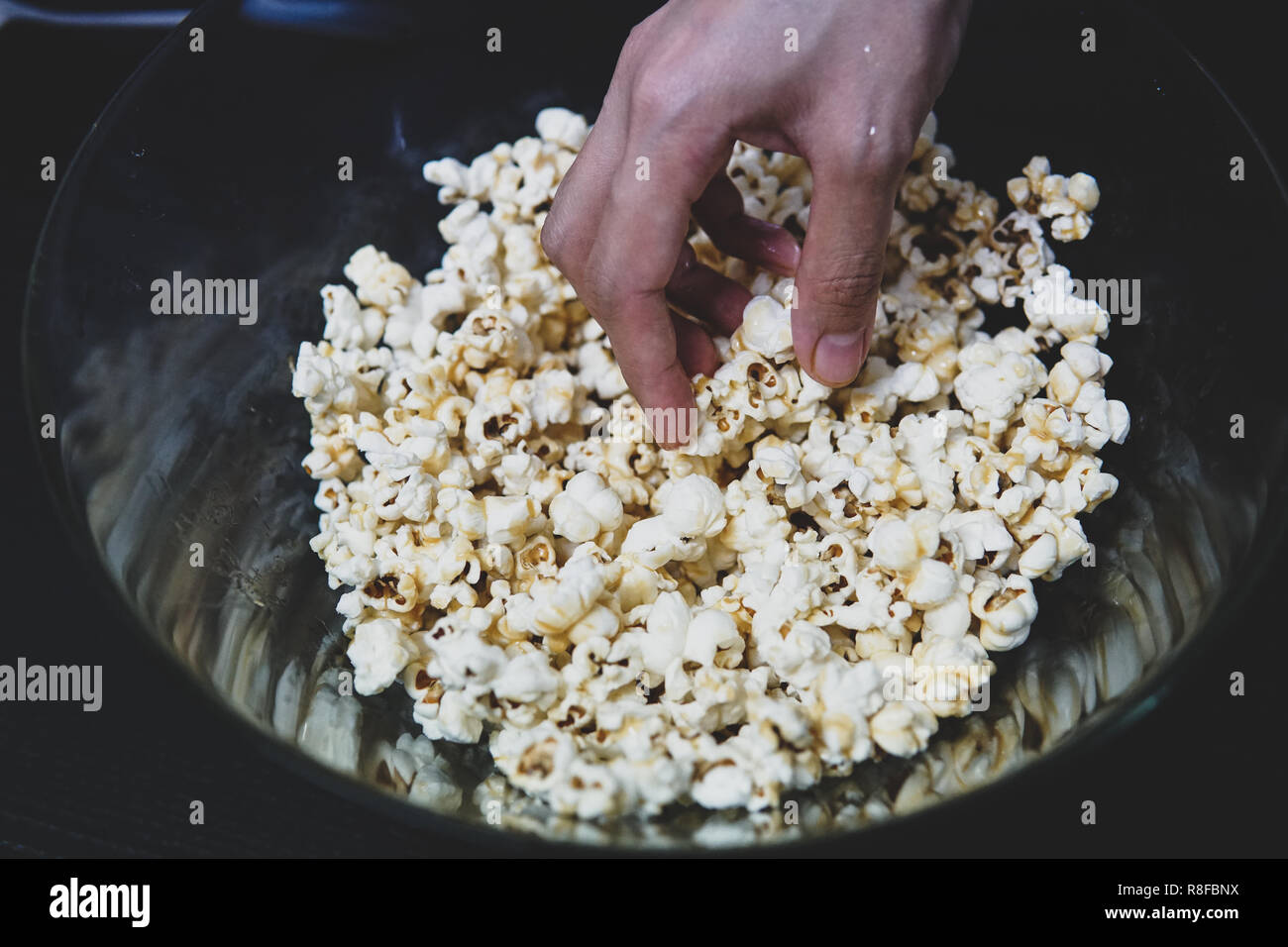 top view of hand grabbing popcorn from bowl Stock Photo - Alamy
